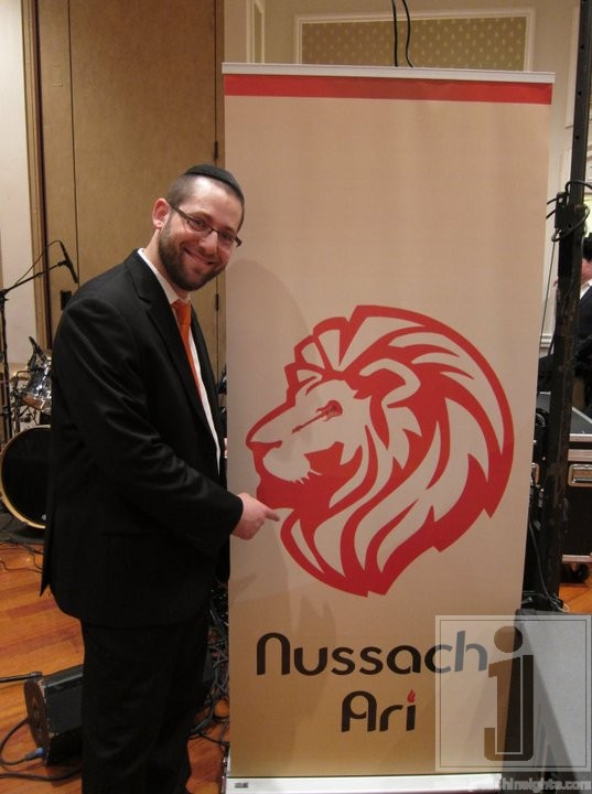 Ari B standing next to the NEW Nusach Ari logo/banner | Jewish Insights
